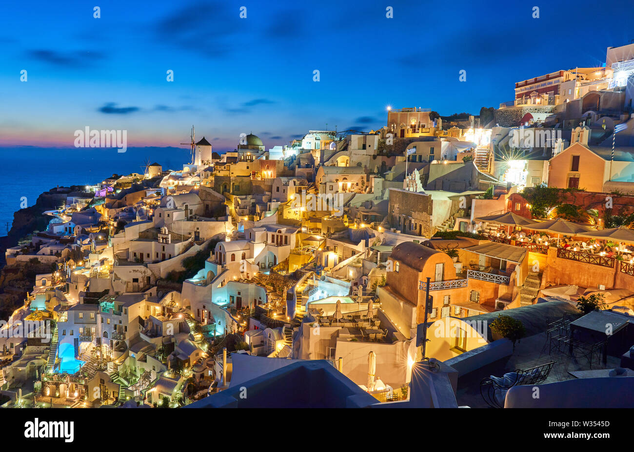 Tourists in luxury restaurants and on Oia Castle wait for the sunset ...