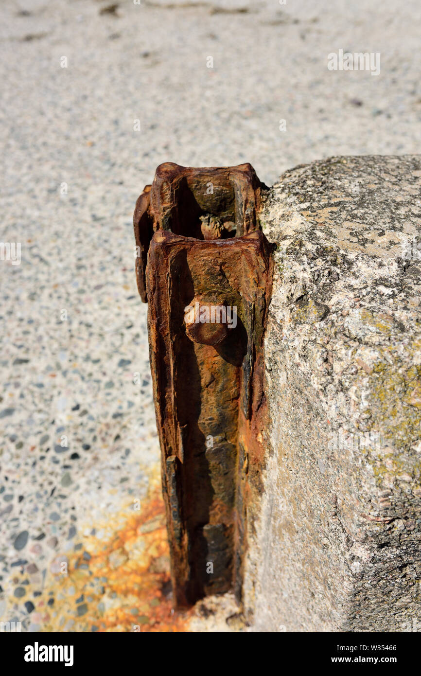 Rusty steel upright post fixed to concrete seawall, coastal flood ...