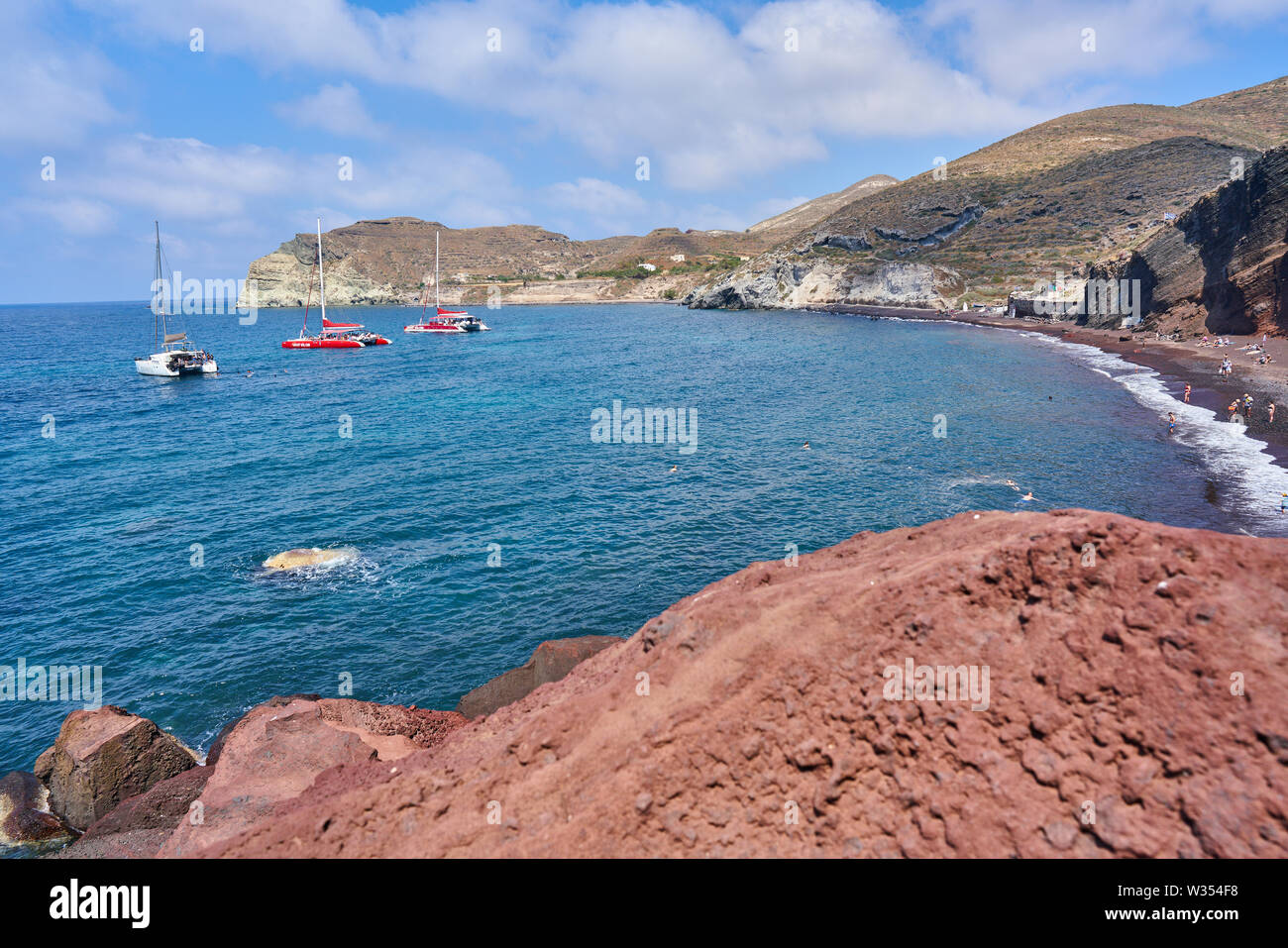 Tourists visit the Red Beach in Akrotiri near Oia, Santorini , Greece ...