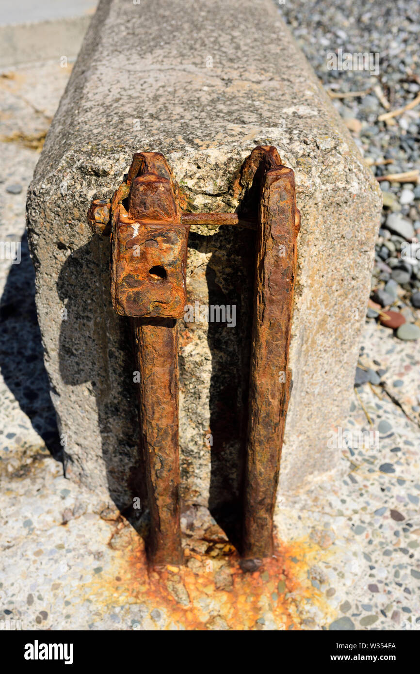 Rusty steel upright post fixed to concrete seawall, coastal flood ...