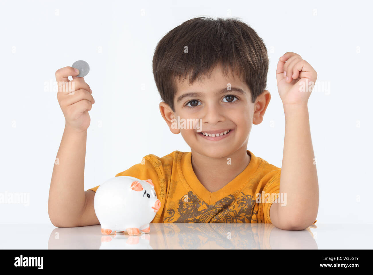 Boy holding coin with a piggy bank and smiling Stock Photo - Alamy