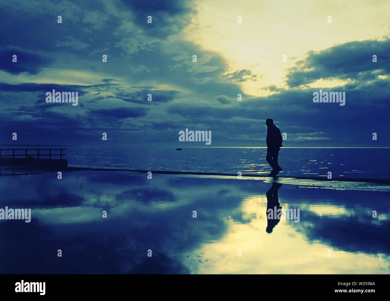 Men walking alone in coast line Stock Photo - Alamy