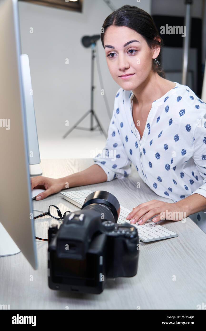 Female Photographer In Studio Reviewing Images From Photo Shoot On ...