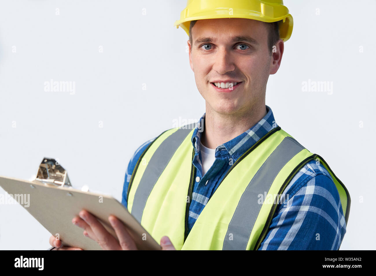 Studio Portrait Of Builder Architect With Clipboard Against White ...
