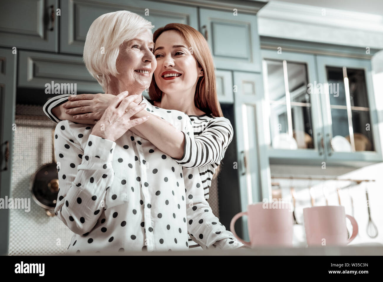 Pleasant meeting. Cheerful middle aged woman kindly hugging her ...