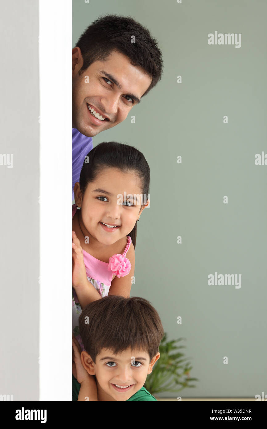 Portrait of a man hiding behind a placard with his children Stock Photo ...