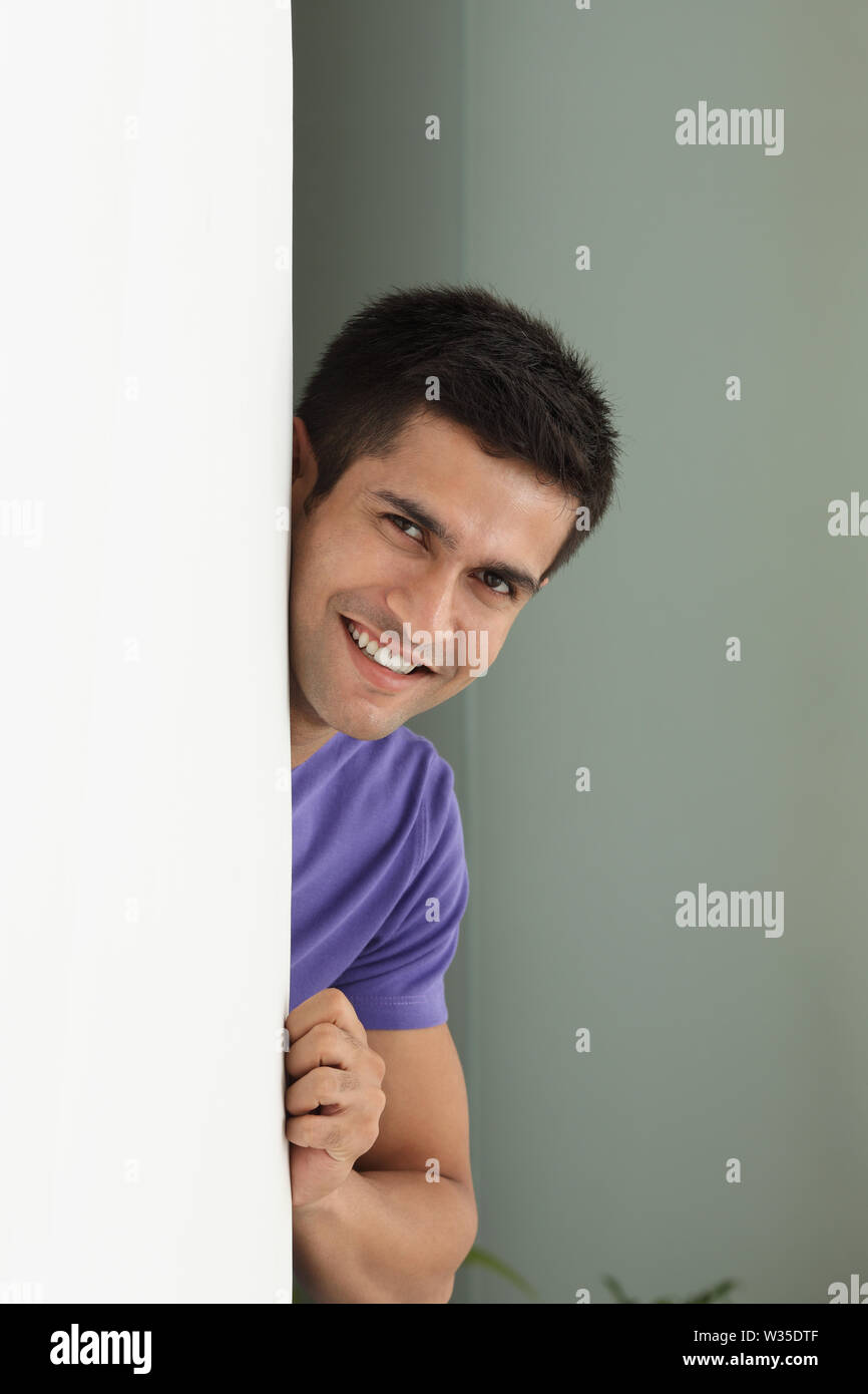 Portrait of a man hiding behind a placard and smiling Stock Photo - Alamy