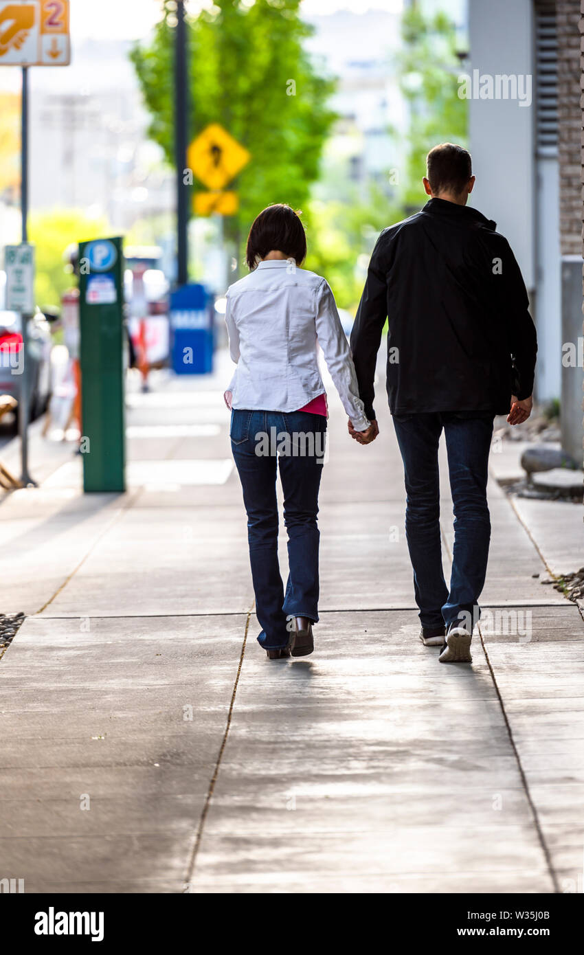Slender curly woman and tall slender man go holding hands on the ...