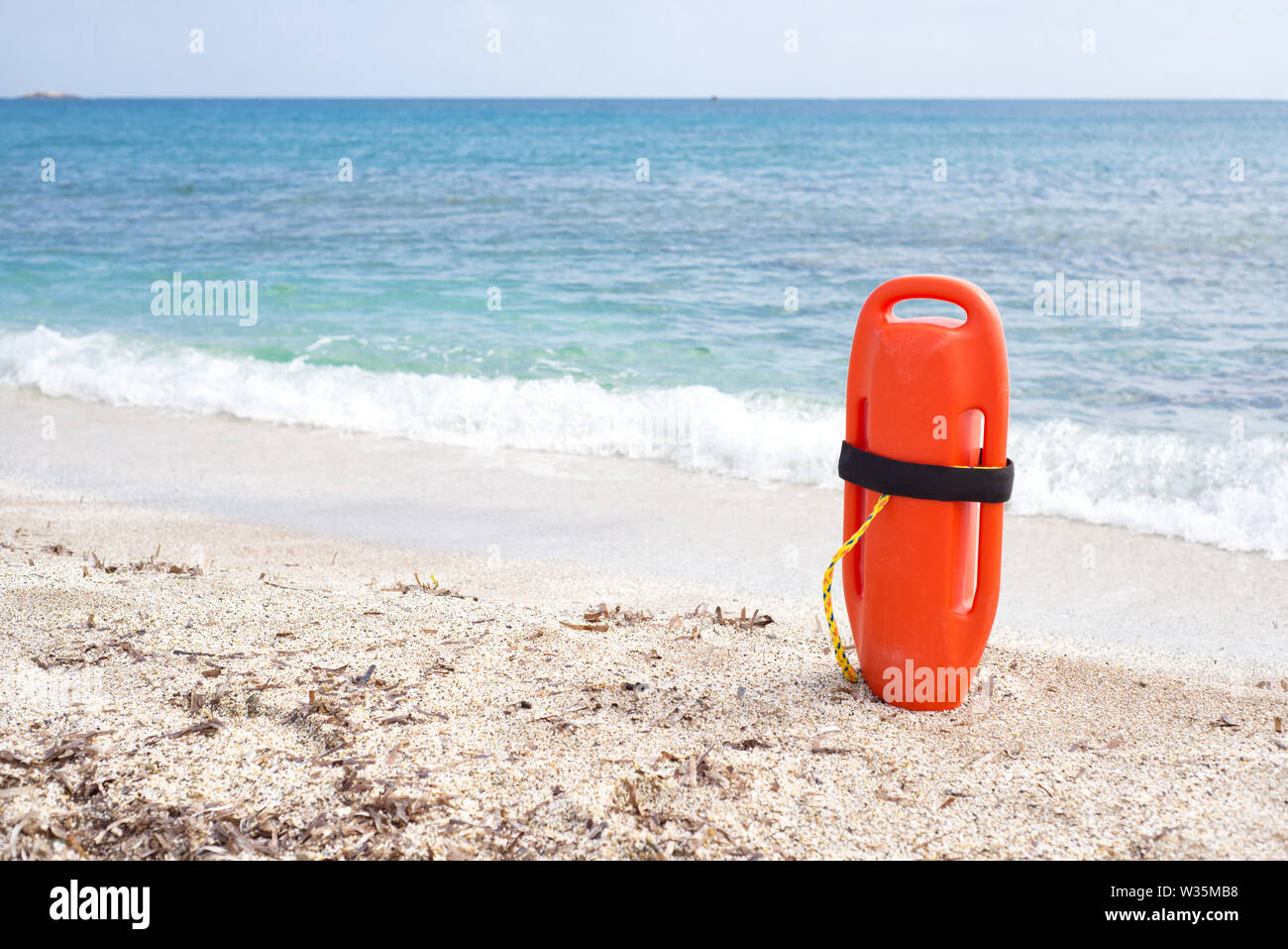 Orange buoy standing on the sand in front of the sea, safety concept ...
