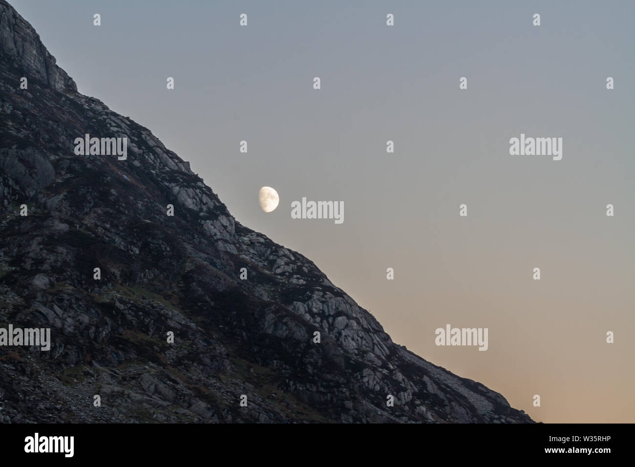 Nearly full moon rising over cliff in Snowdonia Stock Photo - Alamy