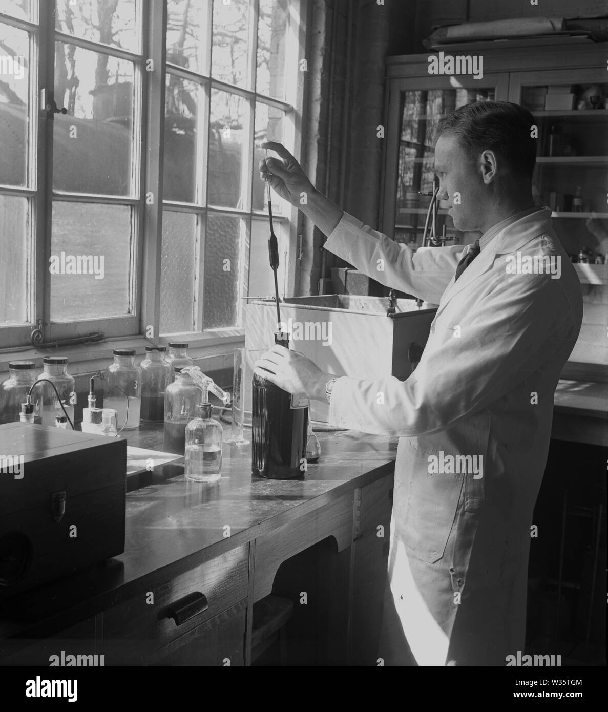 1950s, historical, a male scientist in a white coat standing in a ...