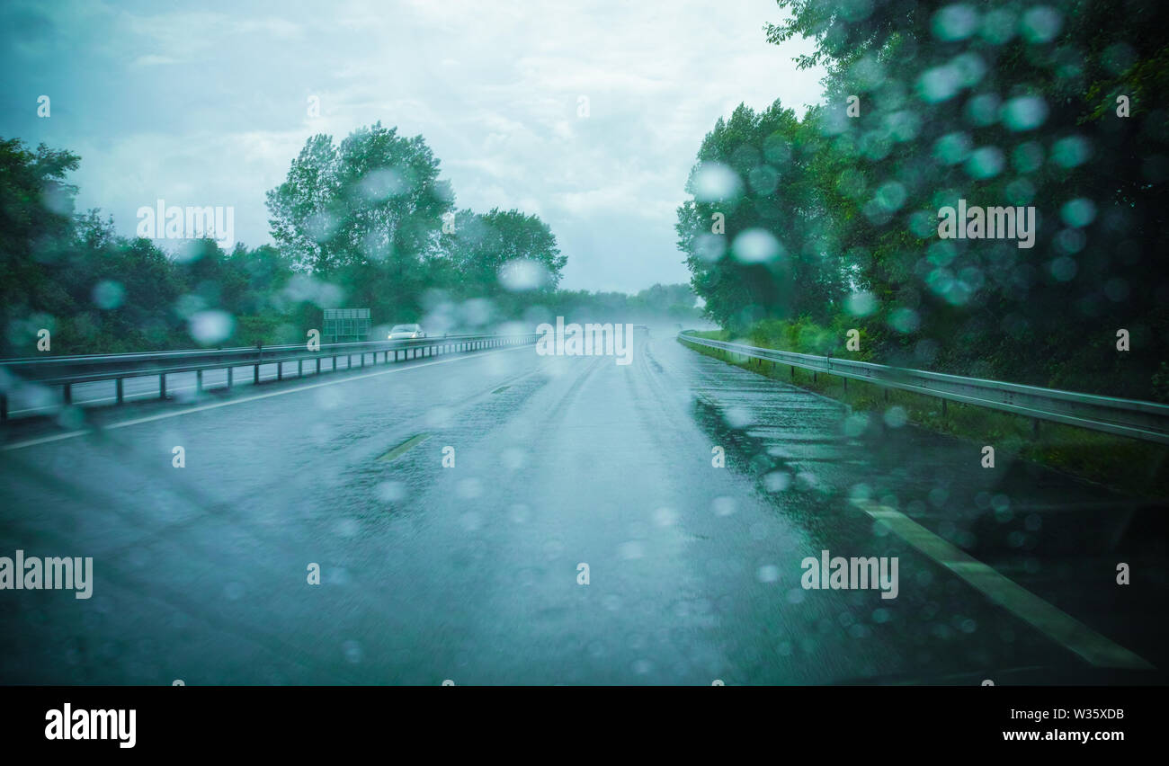 Driving in rain. Car and the road in the rain through the front window ...
