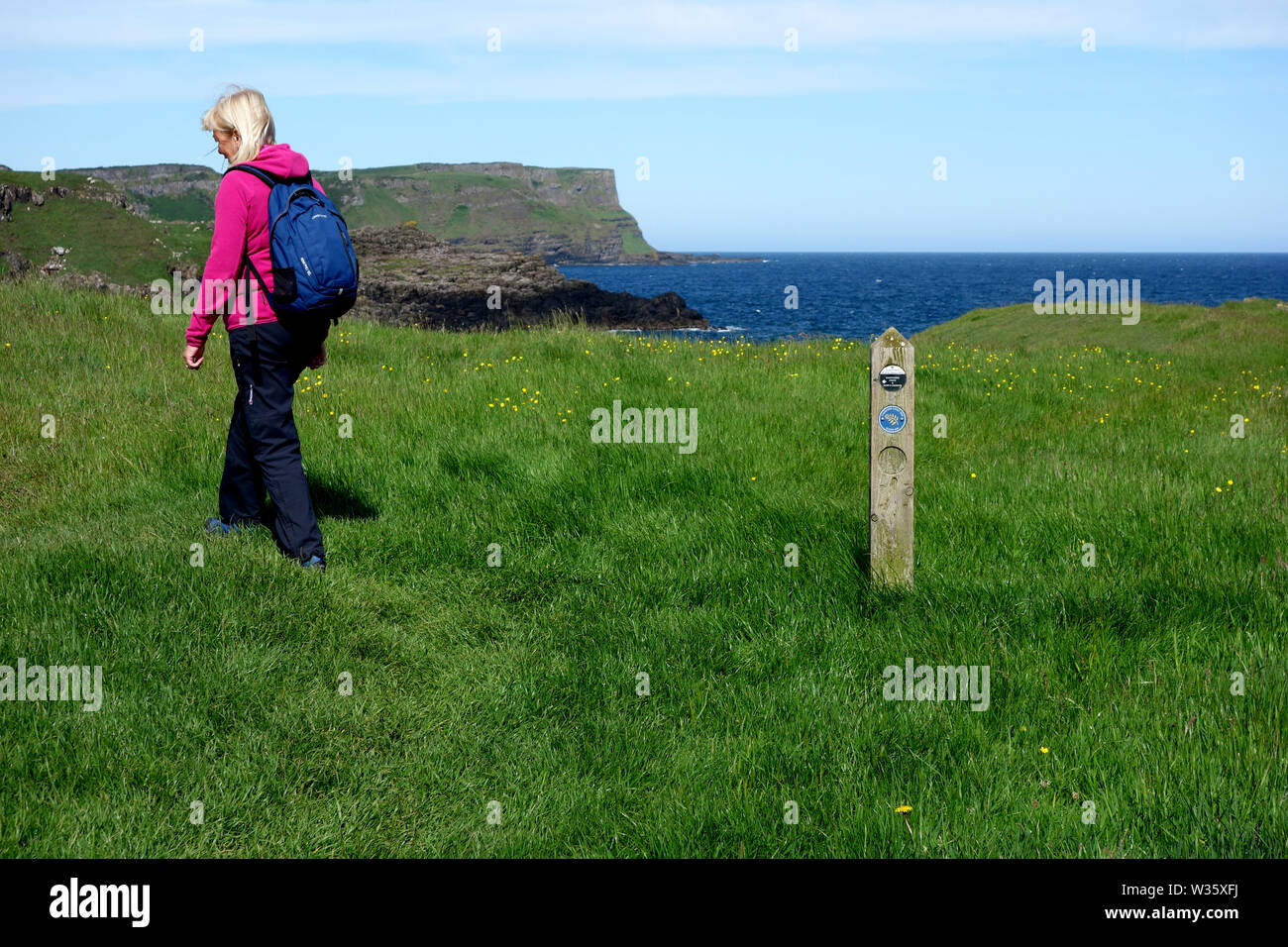 Woman Walking near Dunseverick Harbour with Benbane Head in the ...