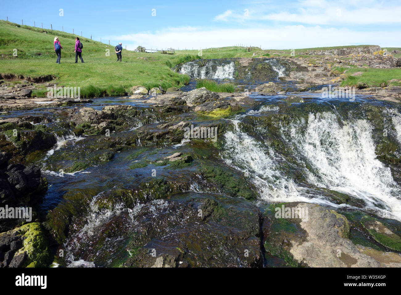 Three People Walking by Waterfalls near Dunseverick Harbour/Castle on ...