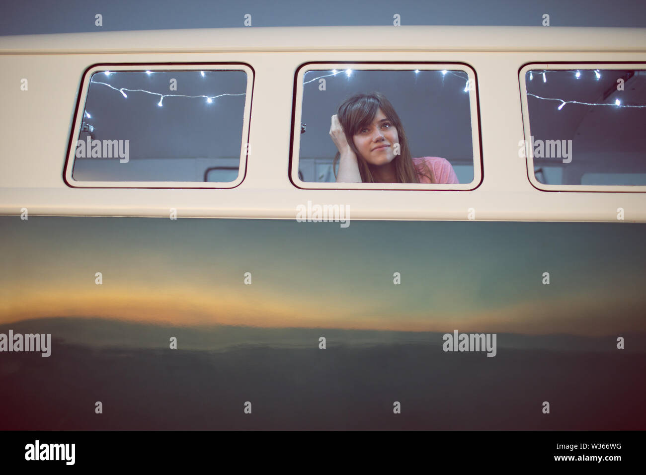 Woman looking through window of a camper van at beach Stock Photo - Alamy