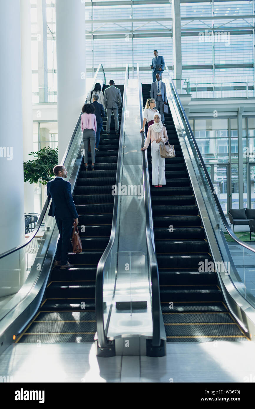 Diverse business people using escalators in modern office Stock Photo ...