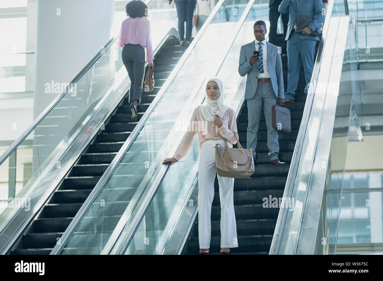 Diverse business people using escalators in modern office Stock Photo ...