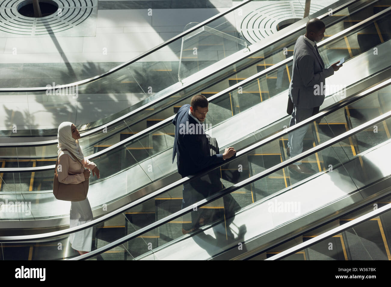 Business people using escalators in modern office Stock Photo - Alamy