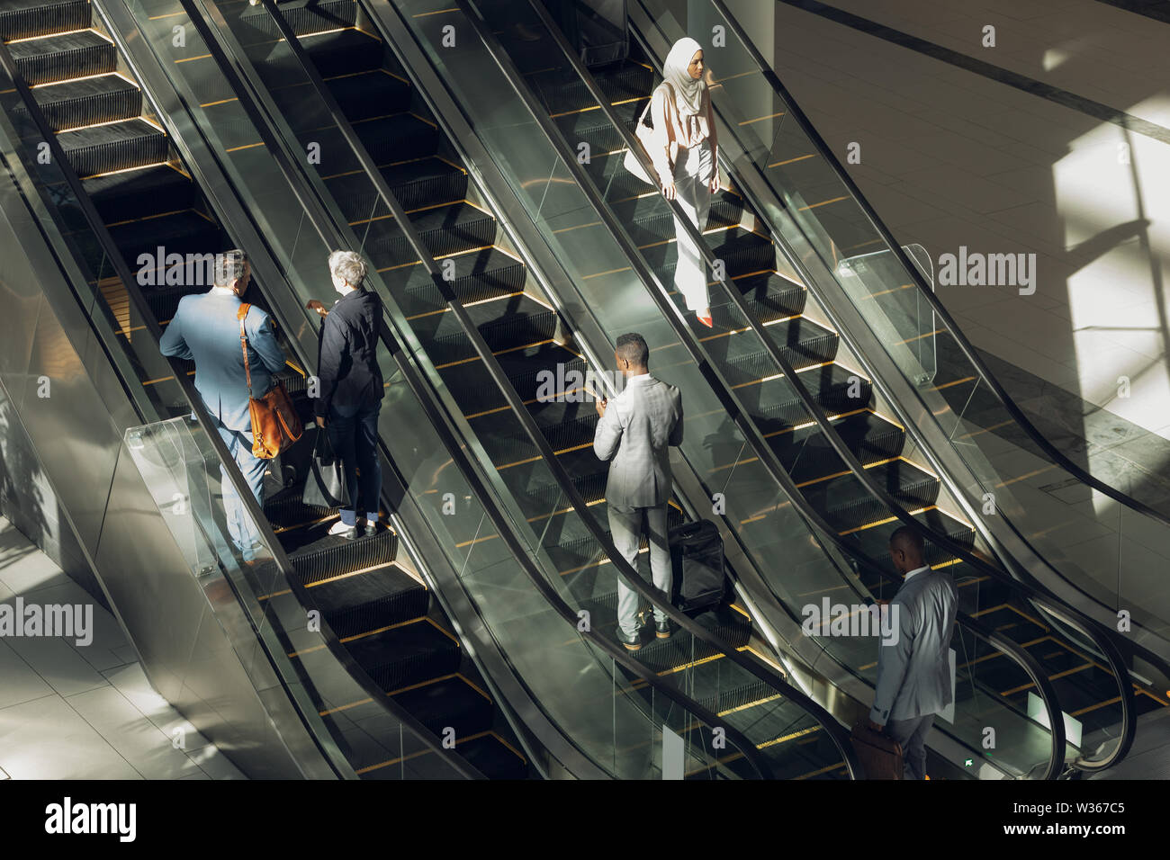 Business people using escalators in modern office Stock Photo - Alamy