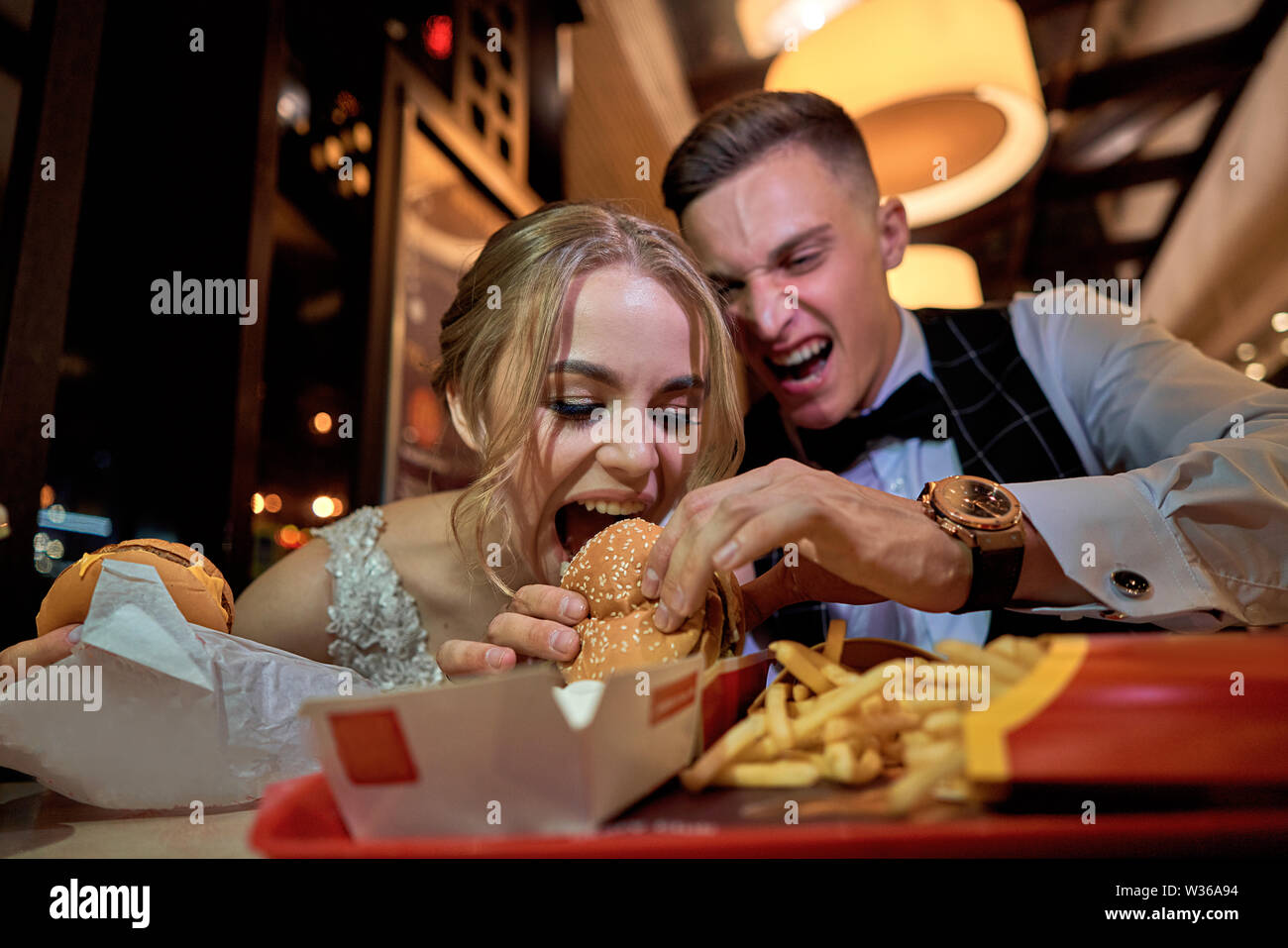 couple eating burgers Stock Photo - Alamy