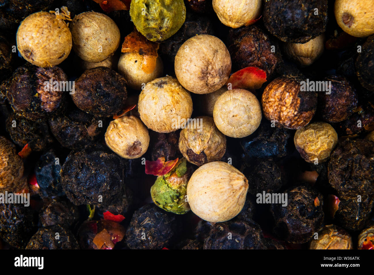 Colored dried pepper mix on. Red, black, white and green pepper close ...