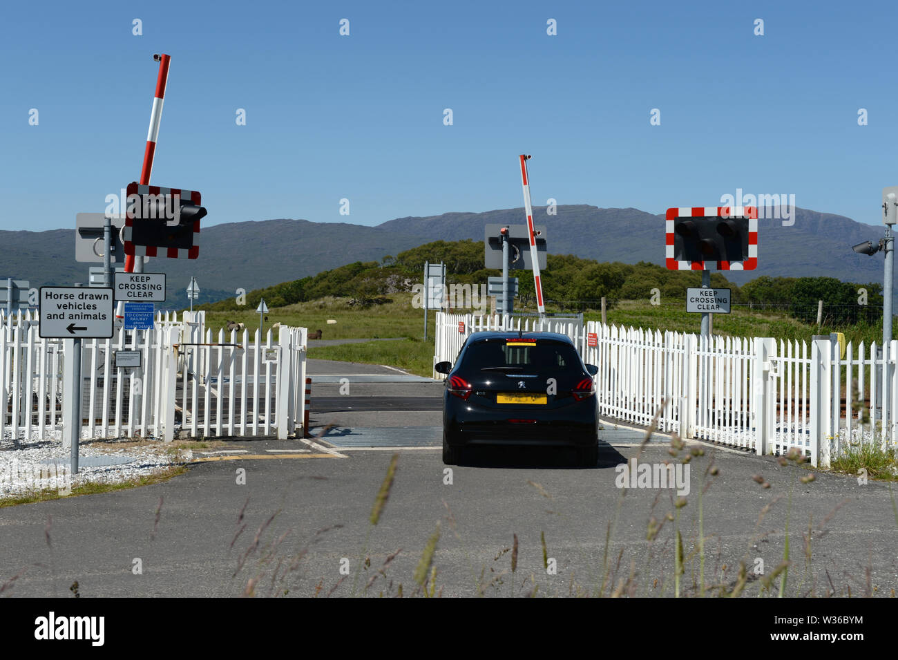 Car approaches railway level crossing. The barriers are raised and no ...