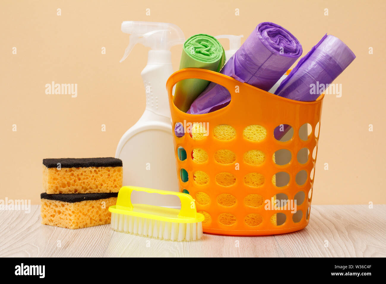 Plastic bottle of glass and tile cleaner, basket with garbage bags ...