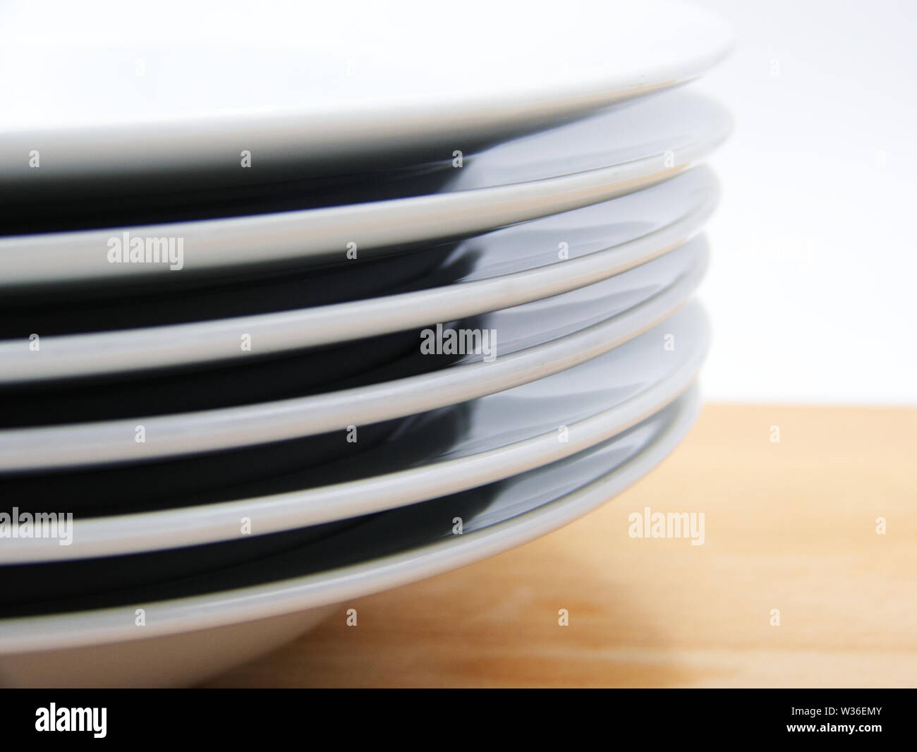 Pile of white plates on wooden table, white background Stock Photo - Alamy