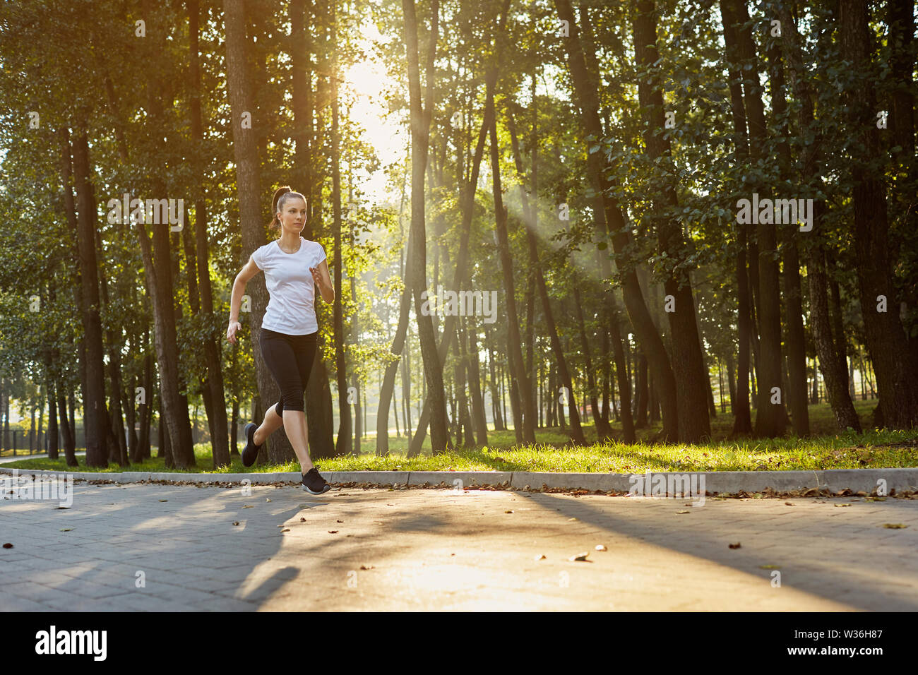 young woman running in park during sunny morning - healthy lifestyle ...