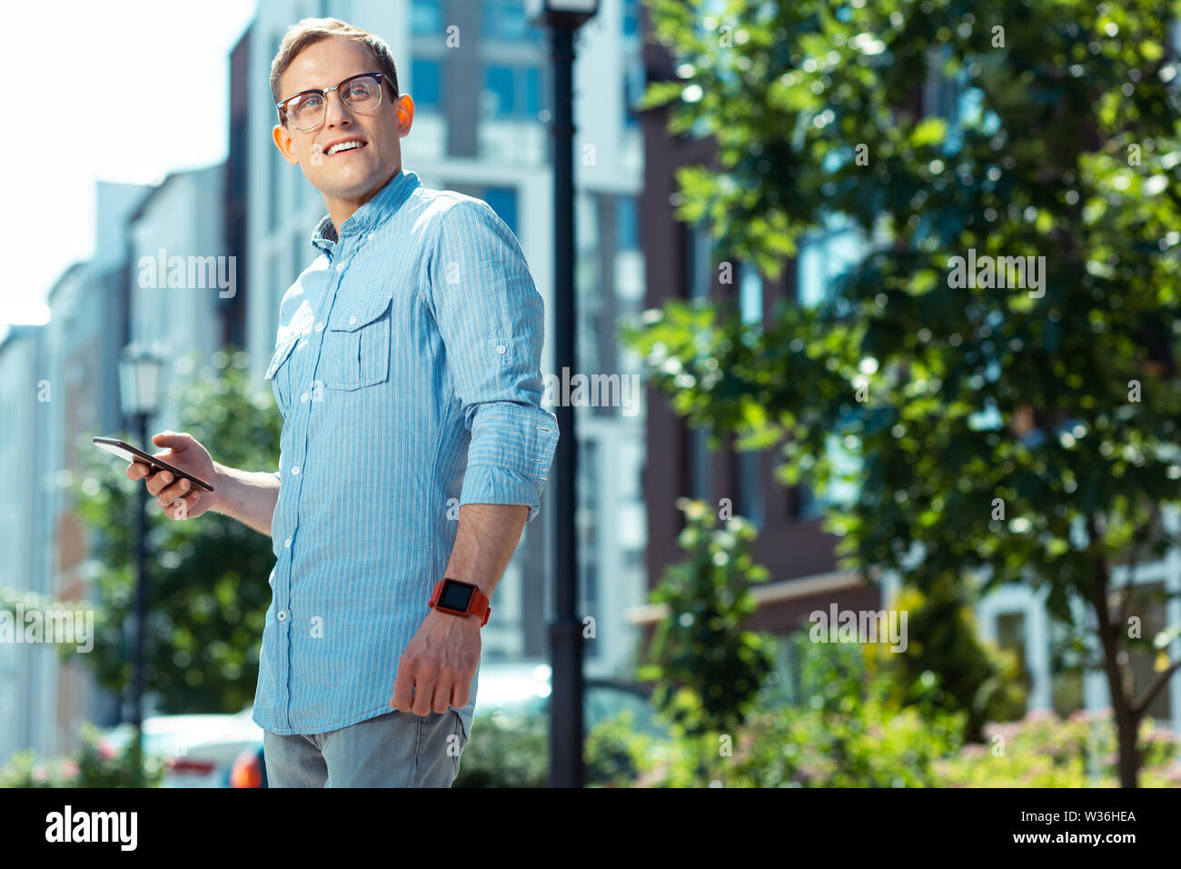 Handsome businessman holding smartphone while standing outside Stock ...
