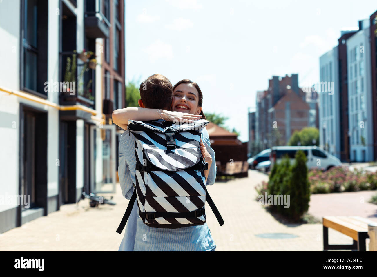 Beaming wife hugging her man wearing backpack Stock Photo - Alamy