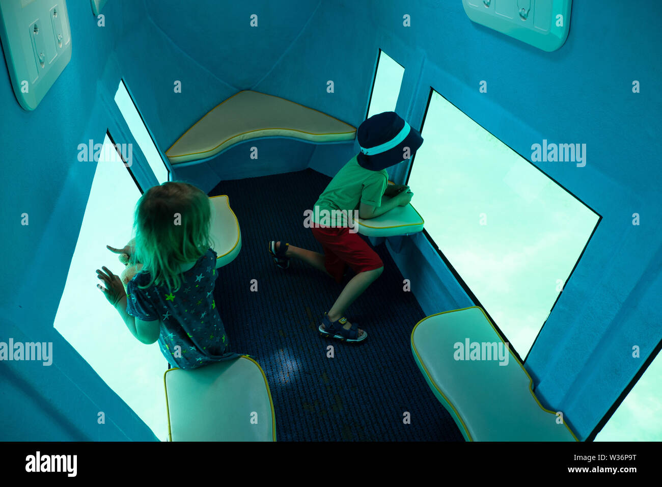 3 and 5 years old kids looking through the window of a glass bottom ...