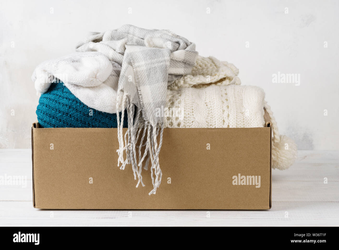 Winter clothes in a cardboard box. Seasonal clothing for shipping or ...