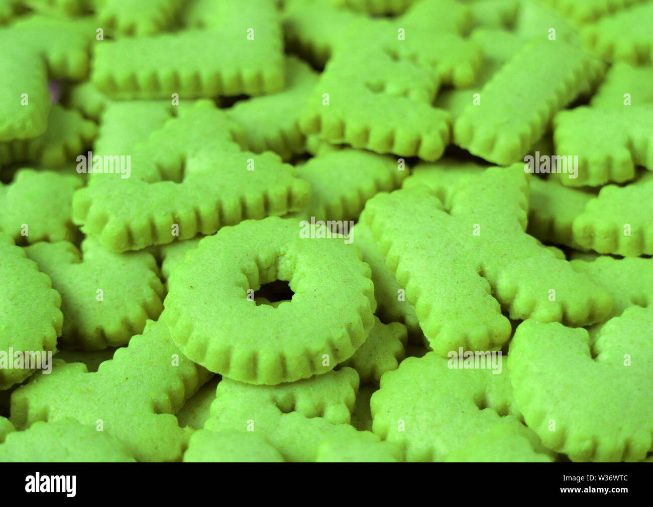 Heap of vibrant lime green alphabet shaped cookies of the letter OK ...