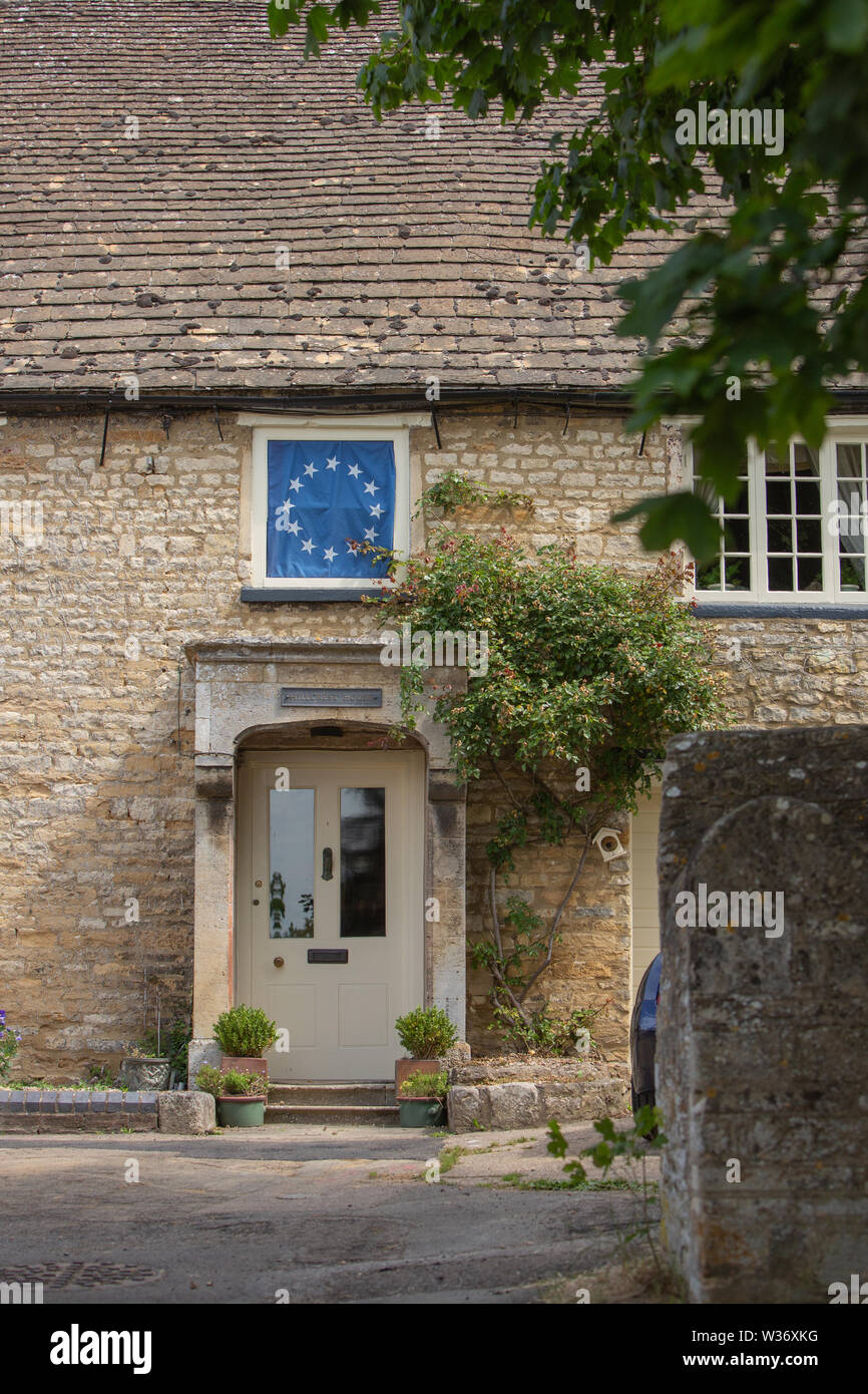 A traditional stone cottage in the UK prominently displaying an EU flag ...