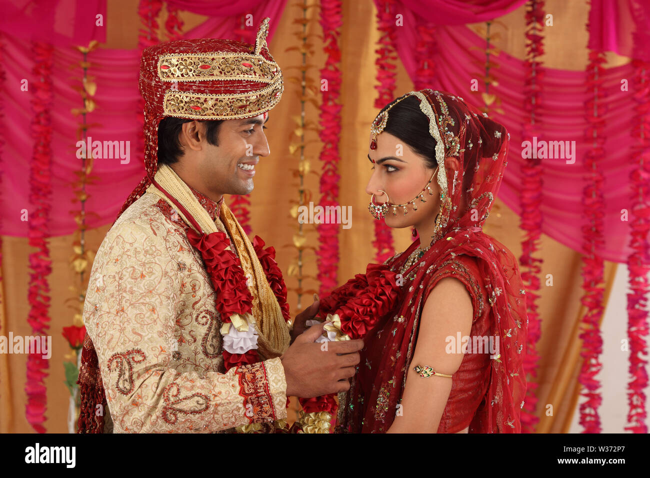 Indian couple performing Mala Badal ceremony in wedding mandap Stock ...