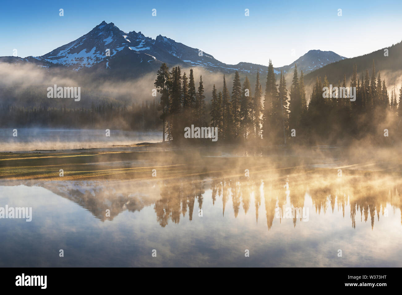 South Sister and Broken Top reflect over the calm waters of Sparks Lake ...