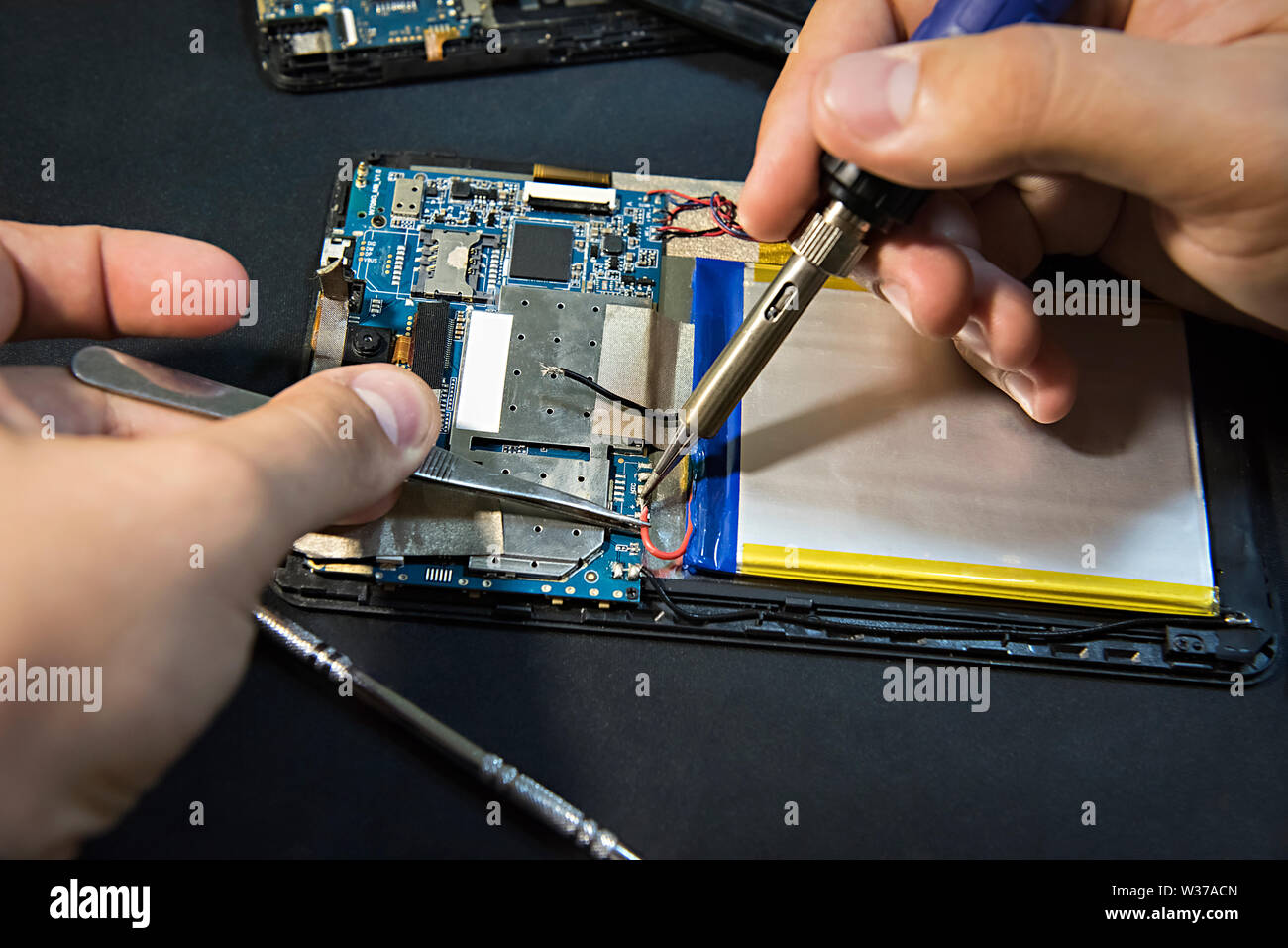 Tablet repair. Soldering the battery contacts Stock Photo - Alamy