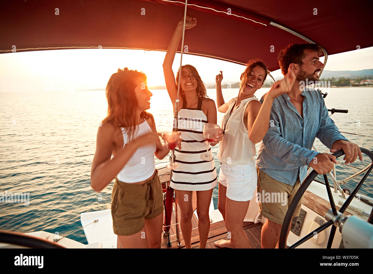 young people on vacation travel on boat together and have fun at sunset ...