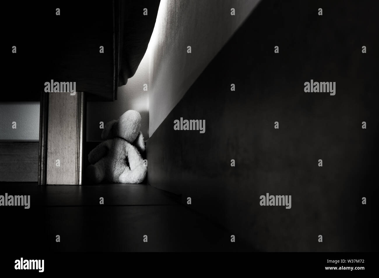 Neglected doll Fall in the dark corner under the bed Stock Photo - Alamy