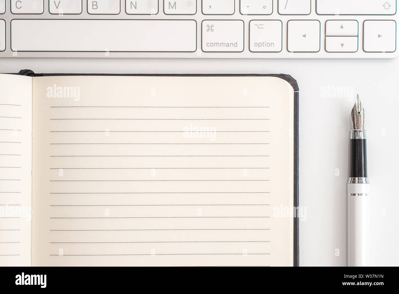 white table with notepad, keyboard and fountain pen. View from above ...