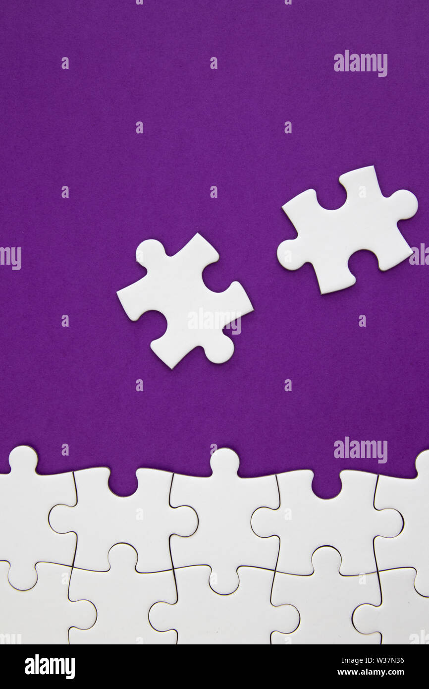 White jigsaw puzzle pieces on purple background with negative space ...