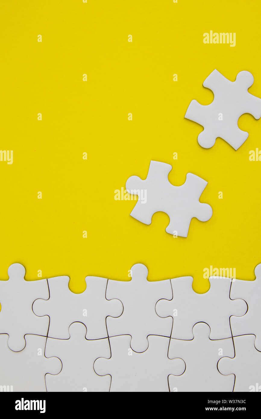 White jigsaw puzzle pieces on yellow background with negative space ...