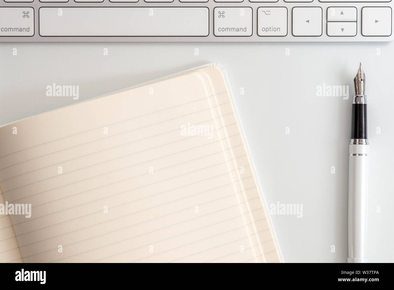 white table with notepad, keyboard and fountain pen. View from above ...