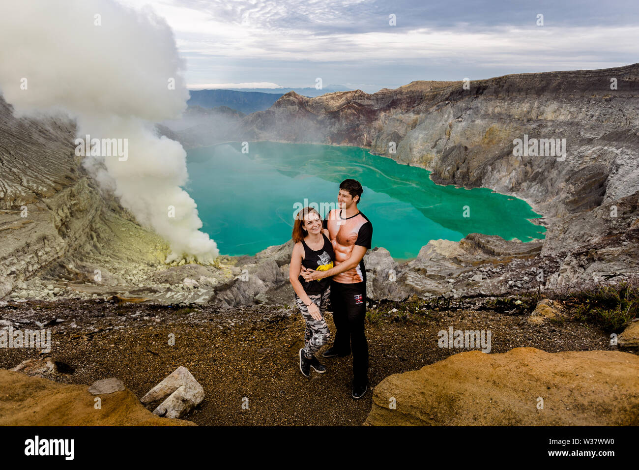 Young couple having fun in the crater of a volcano against the ...