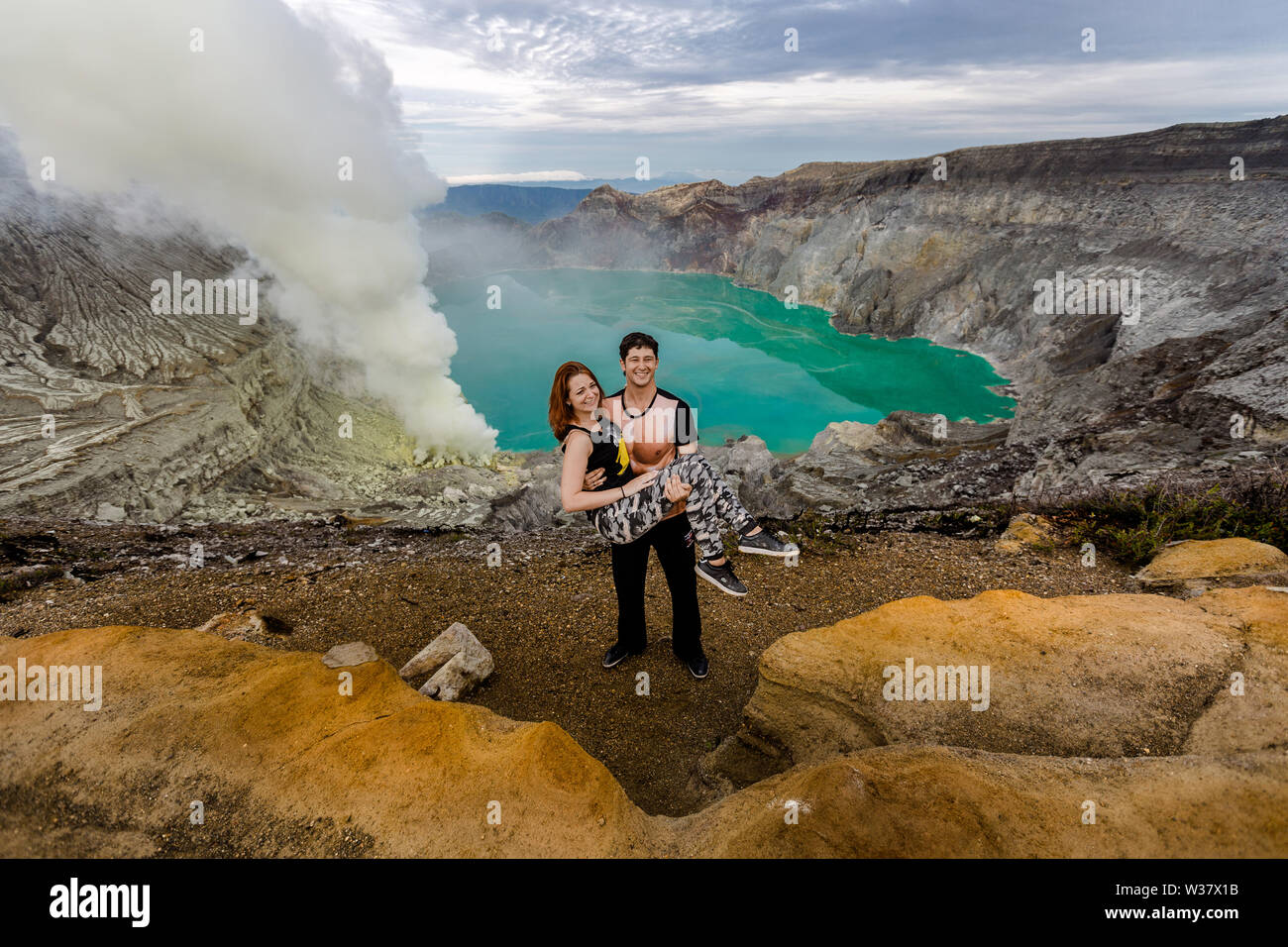 Young couple having fun in the crater of a volcano against the ...