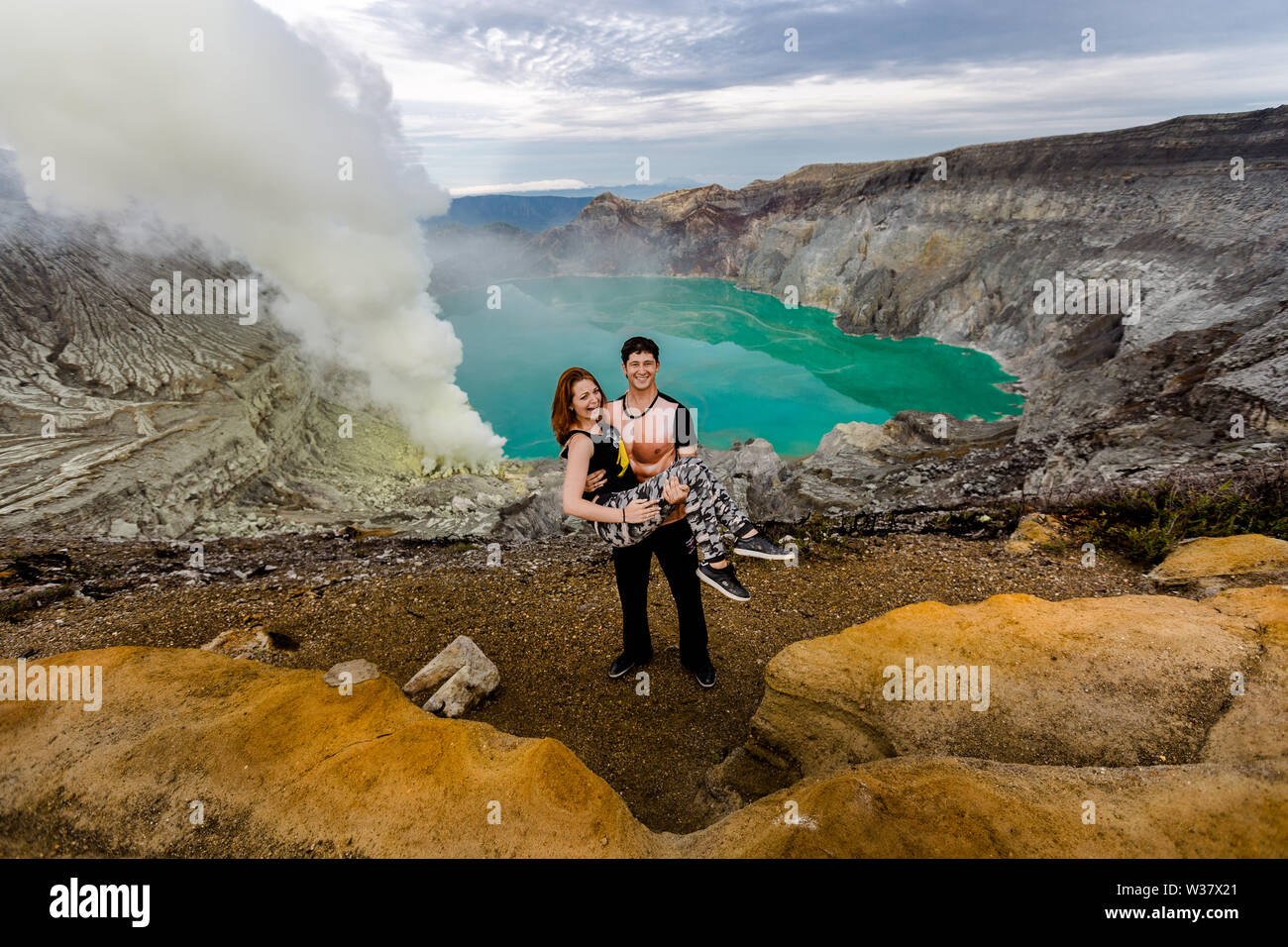Young couple having fun in the crater of a volcano against the ...