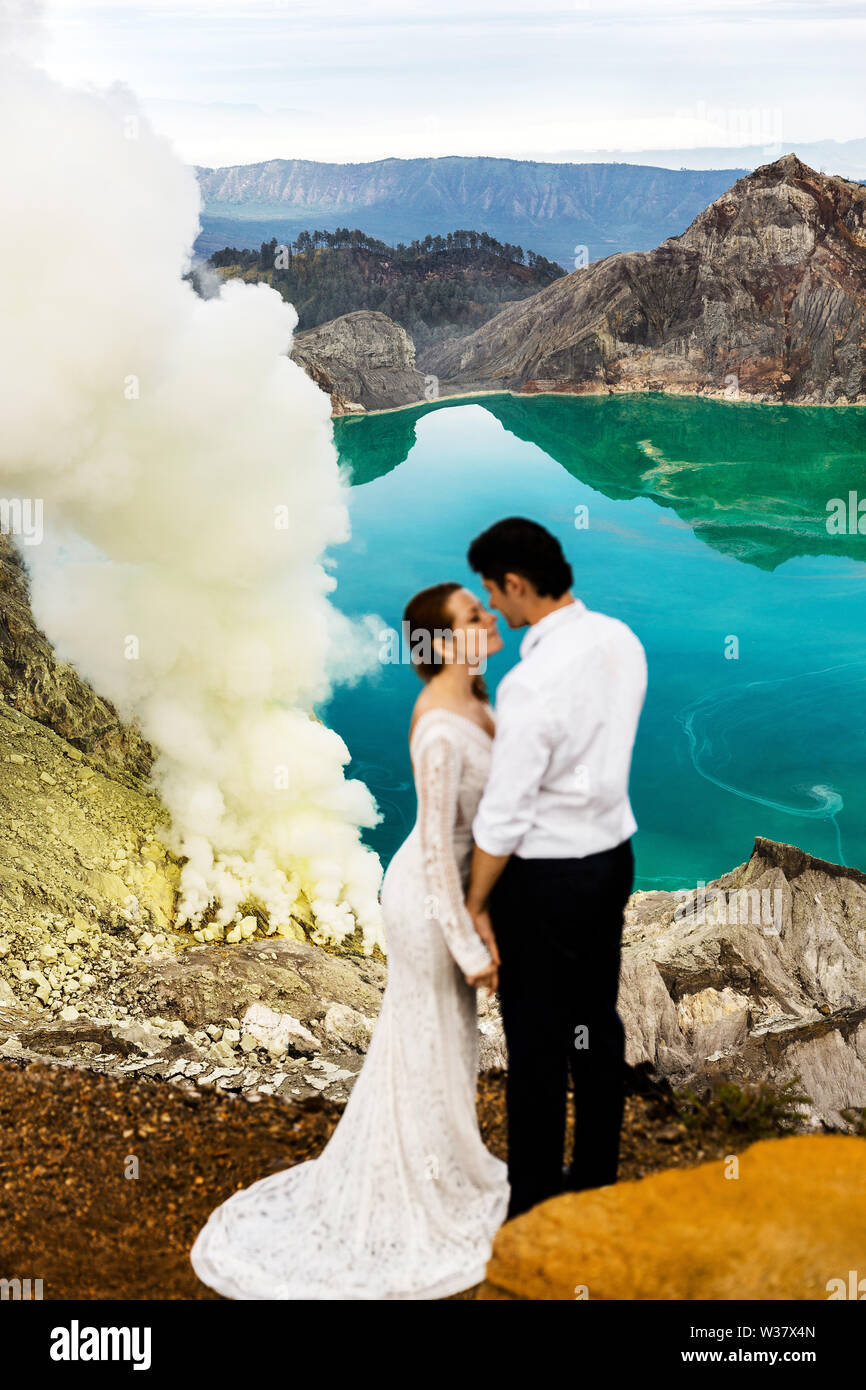 Bride and groom in the crater of a volcano on the background of green ...