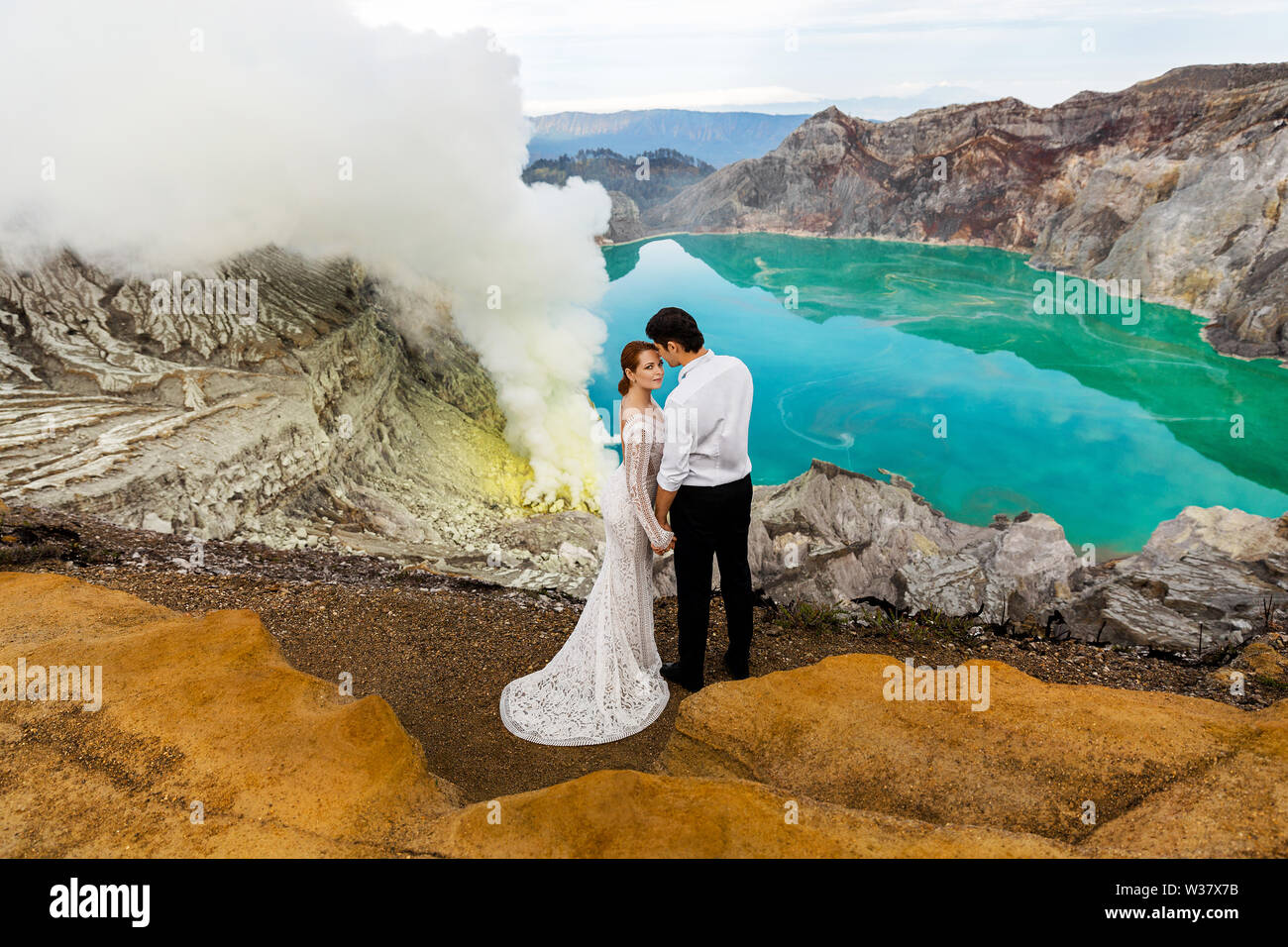 Bride and groom in the crater of a volcano on a background of green ...