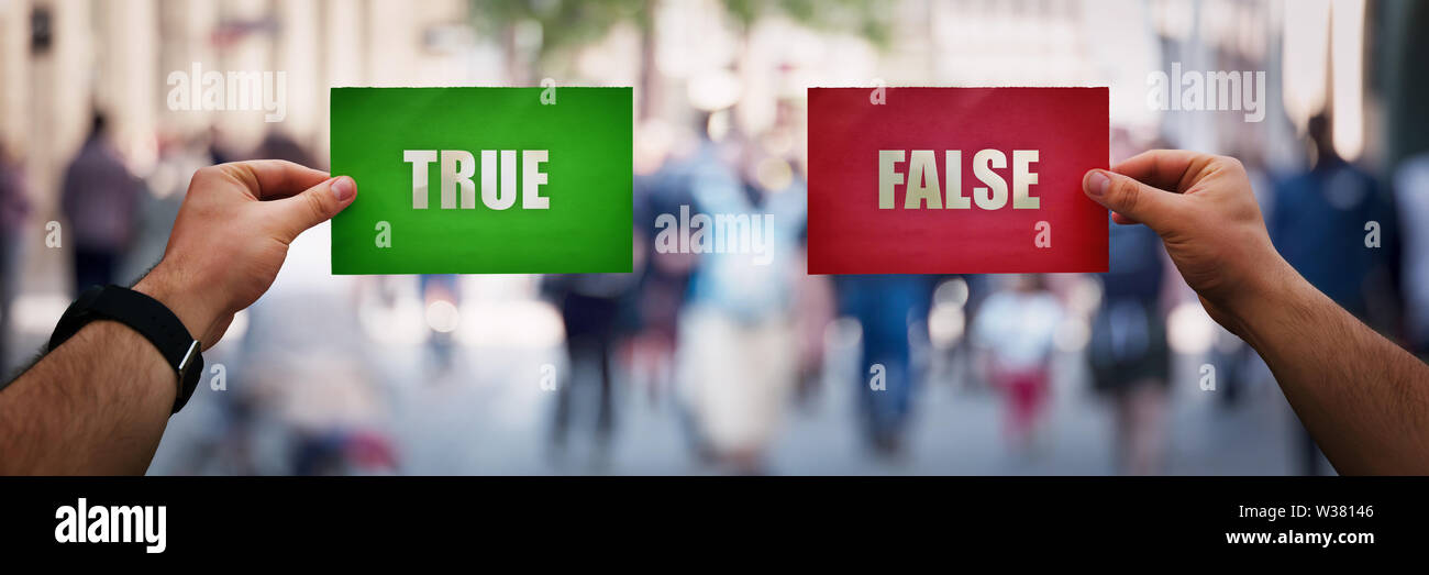 Man hands holding two different colored paper sheets with true and ...